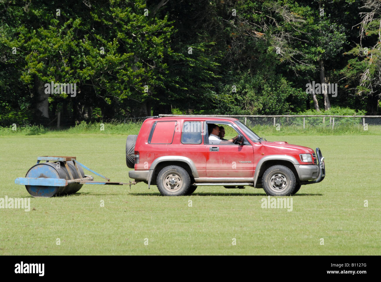 four wheel drive pulling a heavy roller to flatten the ground before a ...