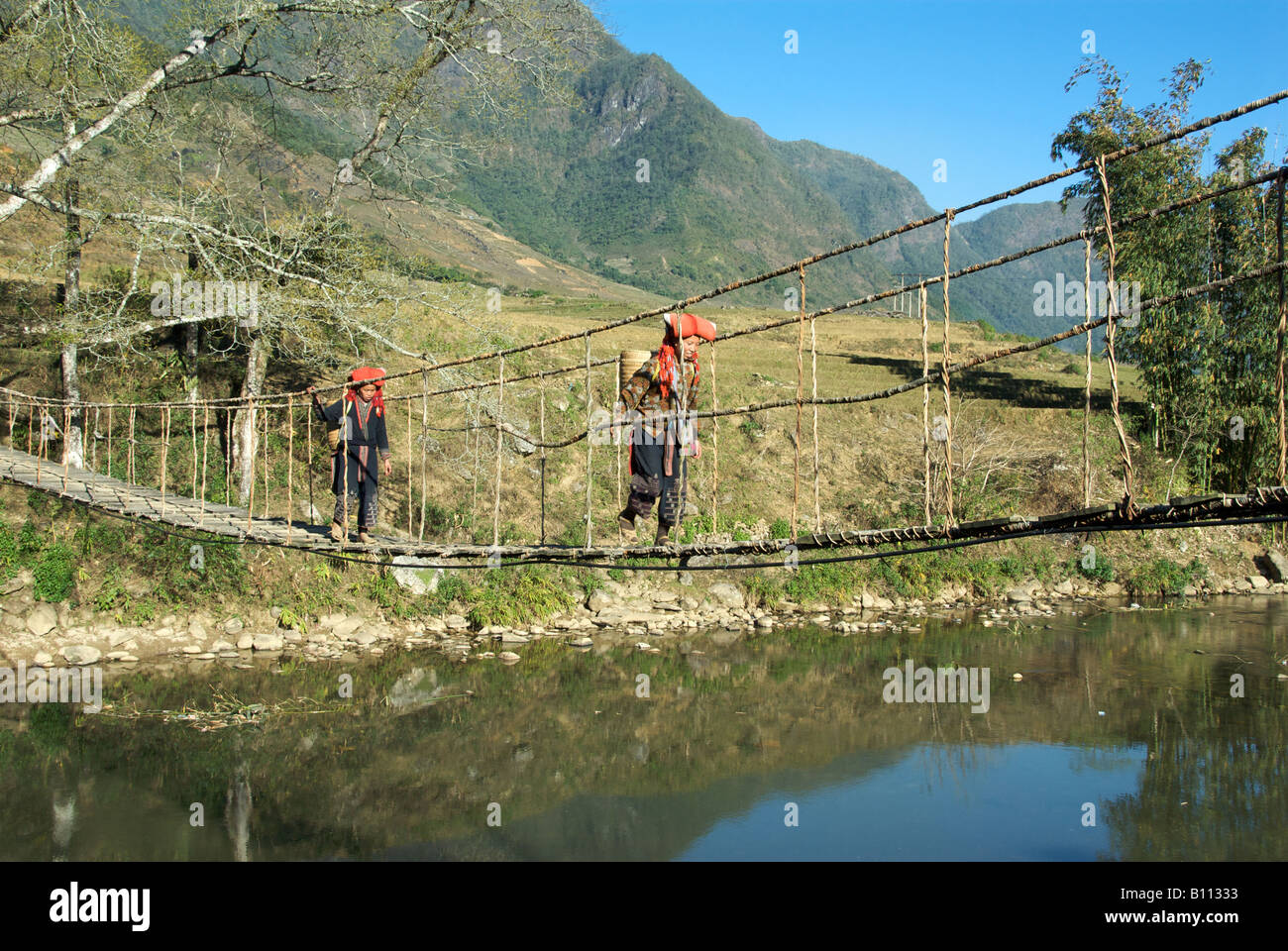 Two Red Dzao women crossing rope bridge Cat Cat Valley near Sapa ...