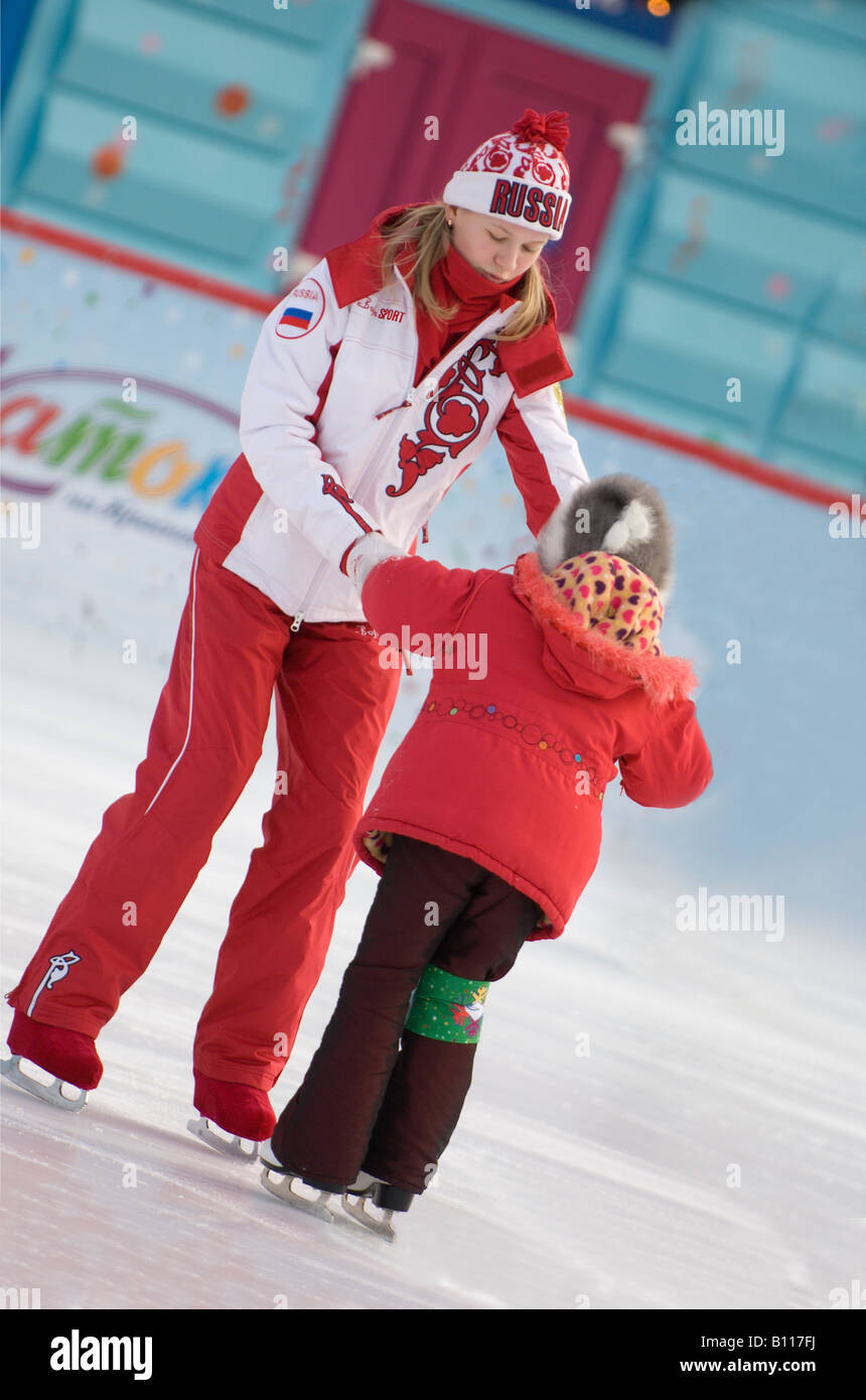A member of the Russian Federation Ice Skating team skates with a child ...