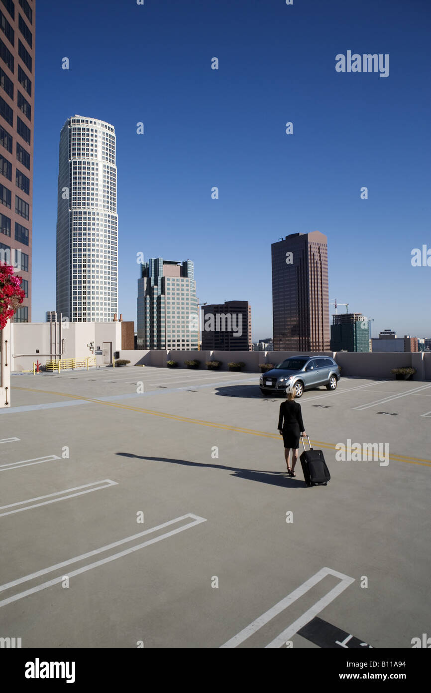 Woman walking towards vehicle with luggage Stock Photo - Alamy