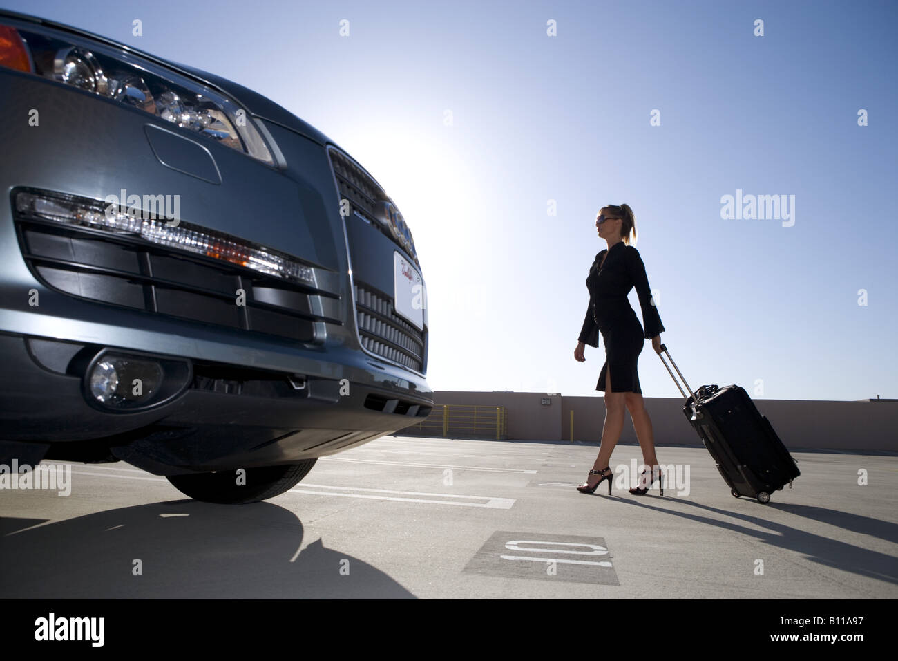 Woman walking towards vehicle with luggage Stock Photo - Alamy