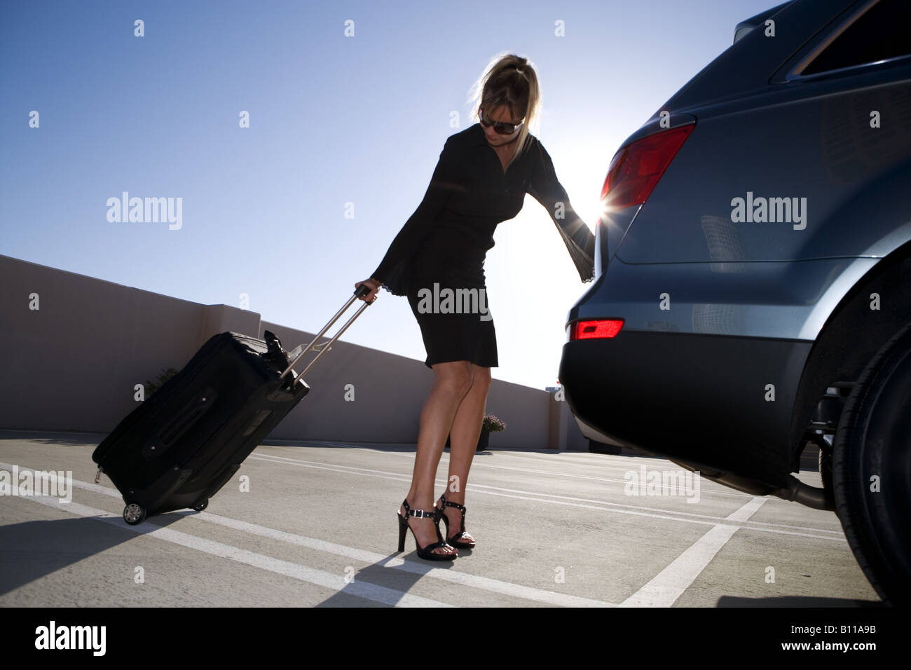 Woman loading luggage into trunk of SUV Stock Photo - Alamy