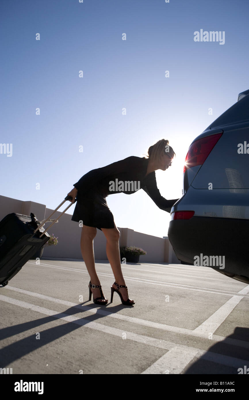 Woman loading luggage into trunk of SUV Stock Photo - Alamy