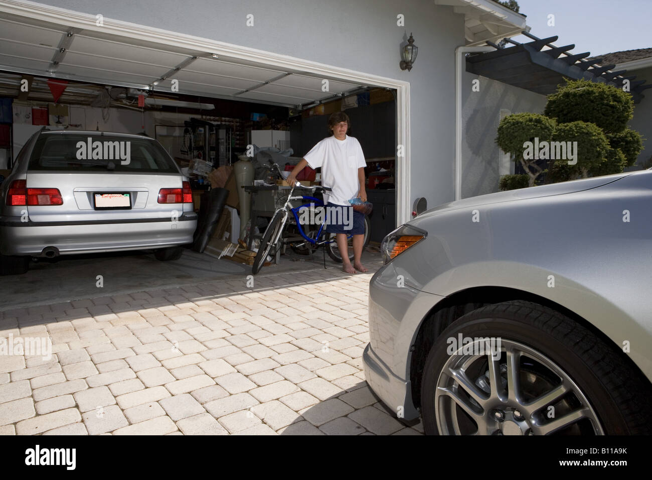 Teenage boy in garage with bike Stock Photo - Alamy
