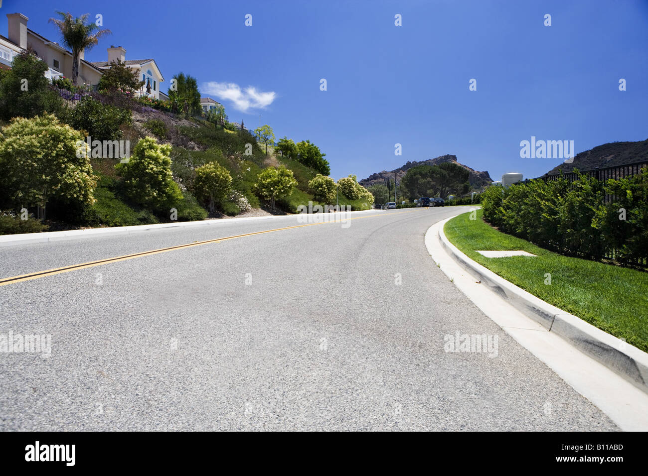 Curve in road leading to residential neighborhood Stock Photo - Alamy