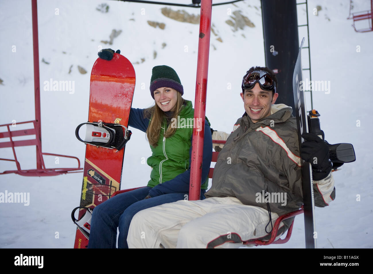 Young couple sit on ski lift chair on snowy hillside Stock Photo - Alamy