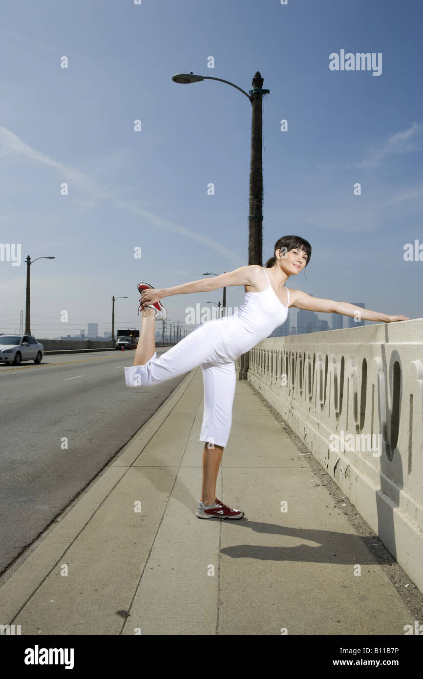 Woman stretching on urban bridge Stock Photo - Alamy