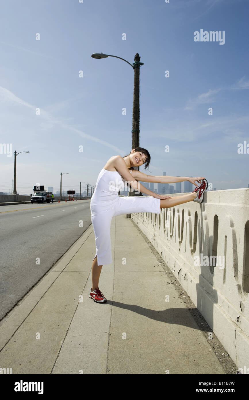Woman stretching on urban bridge Stock Photo - Alamy