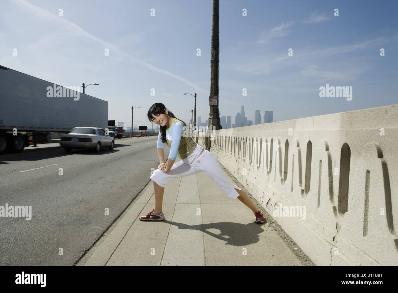 Woman stretching on urban bridge Stock Photo - Alamy