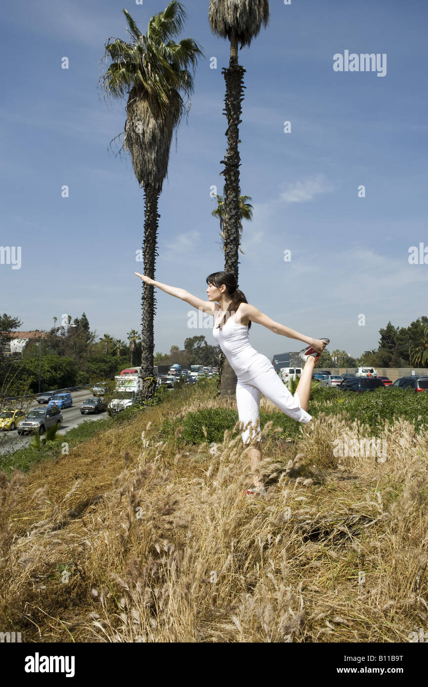 Woman performing yoga by busy freeway Stock Photo - Alamy