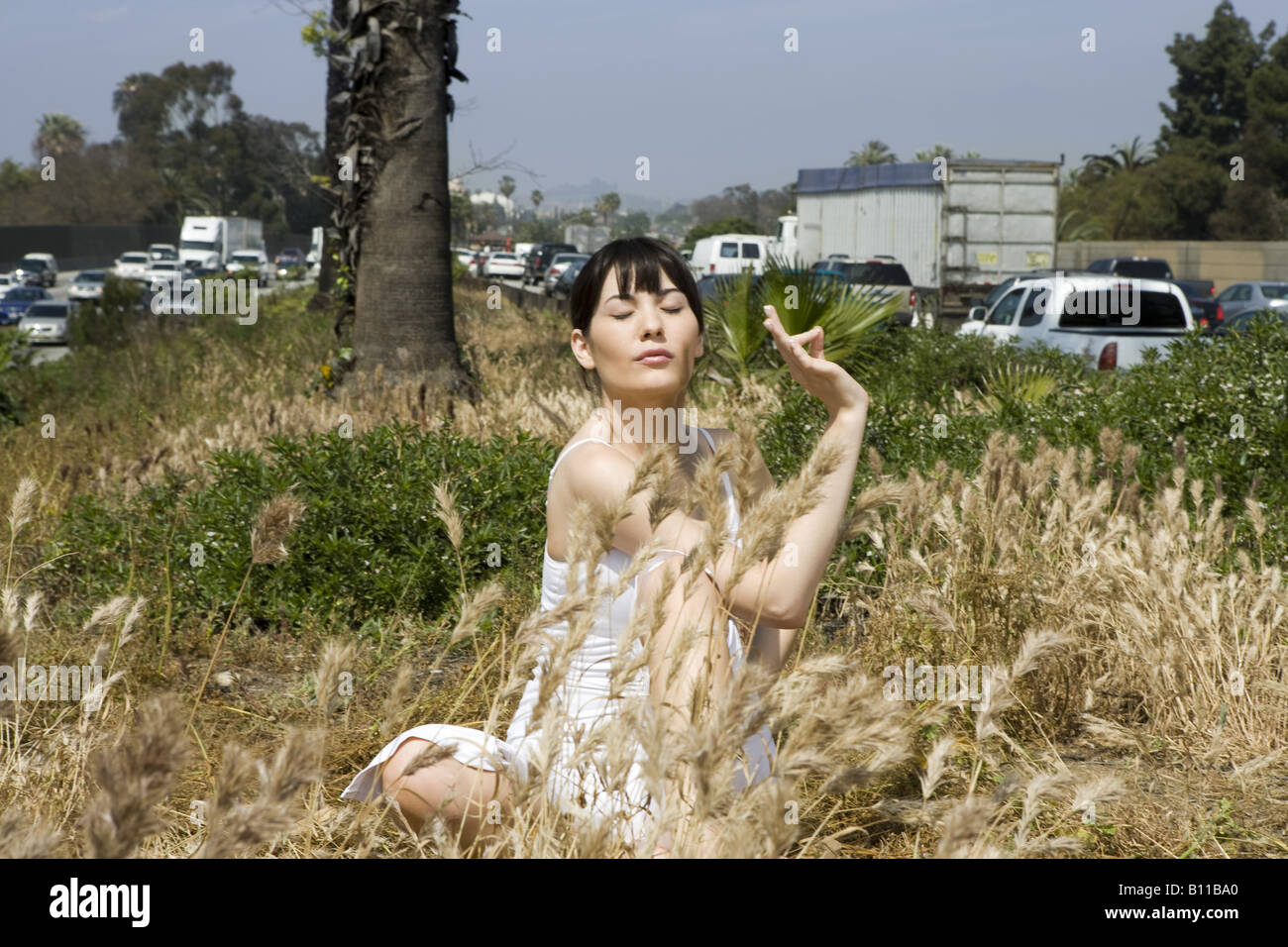 Woman performing yoga by busy freeway Stock Photo - Alamy