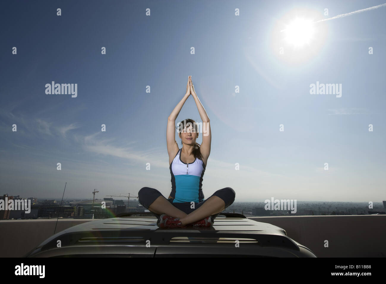 Woman performing yoga on top of SUV on roof top car park Stock Photo ...