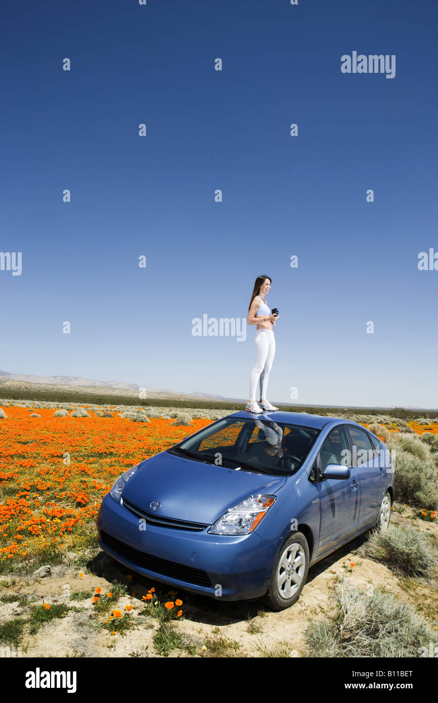 Young woman standing on top of blue Toyota Prius holding camera Stock ...