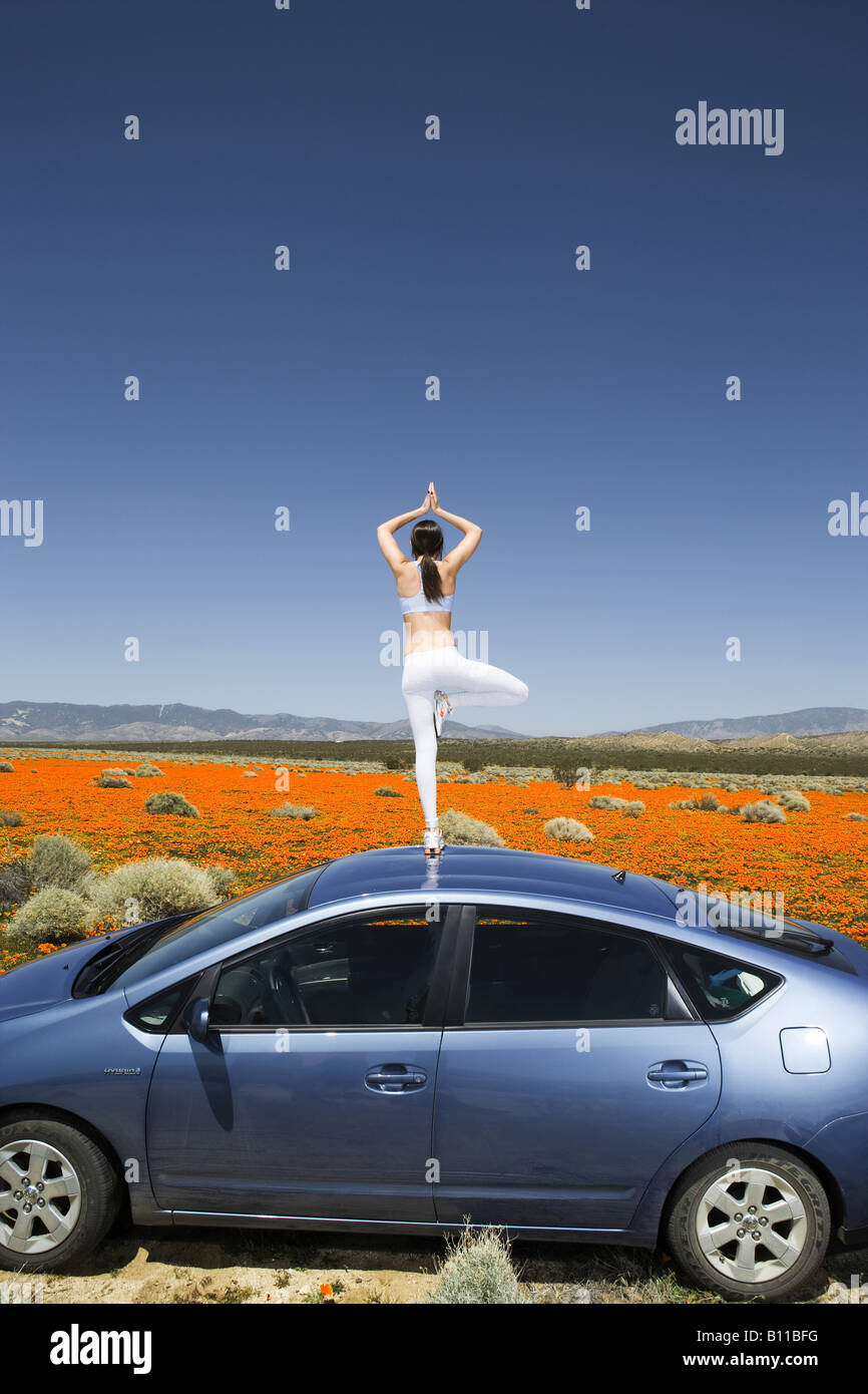 Young woman practicing yoga on roof of blue Toyota Prius Stock Photo ...