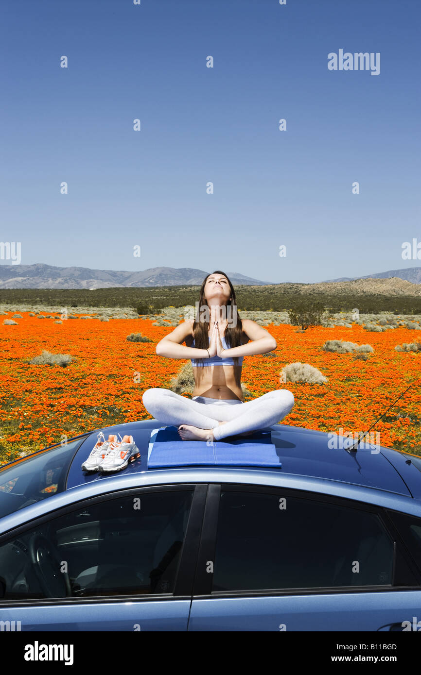 Young woman practicing yoga on roof of blue Toyota Prius Stock Photo ...