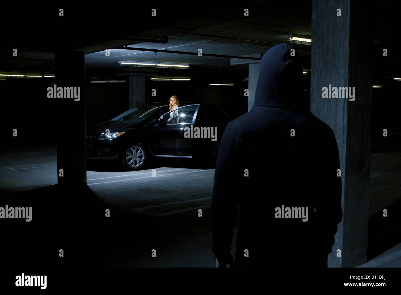 Woman sees prowler as she enters car in car park Stock Photo - Alamy