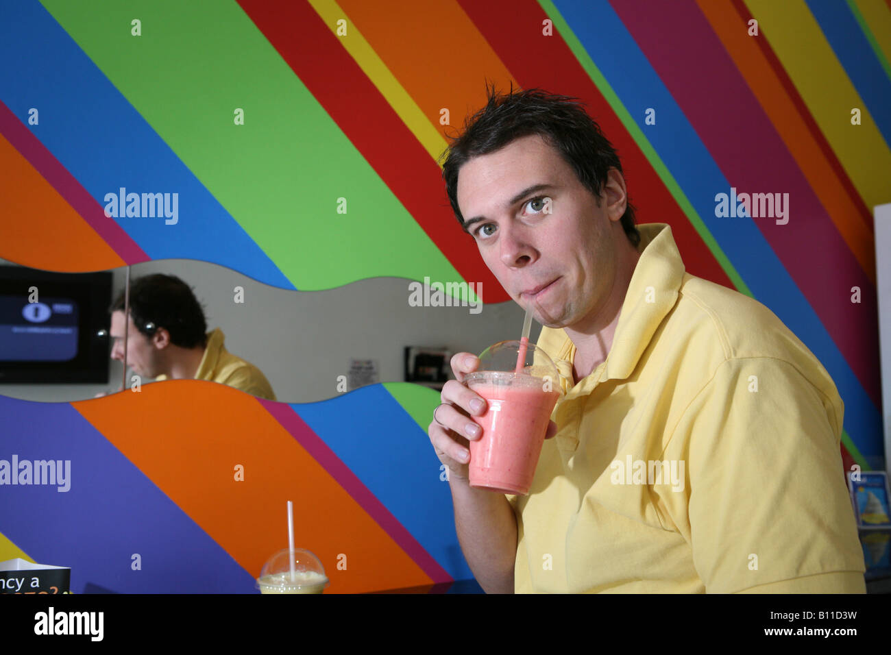 a happy male customer drinking a fruit smoothie in a smoothie bar Stock ...