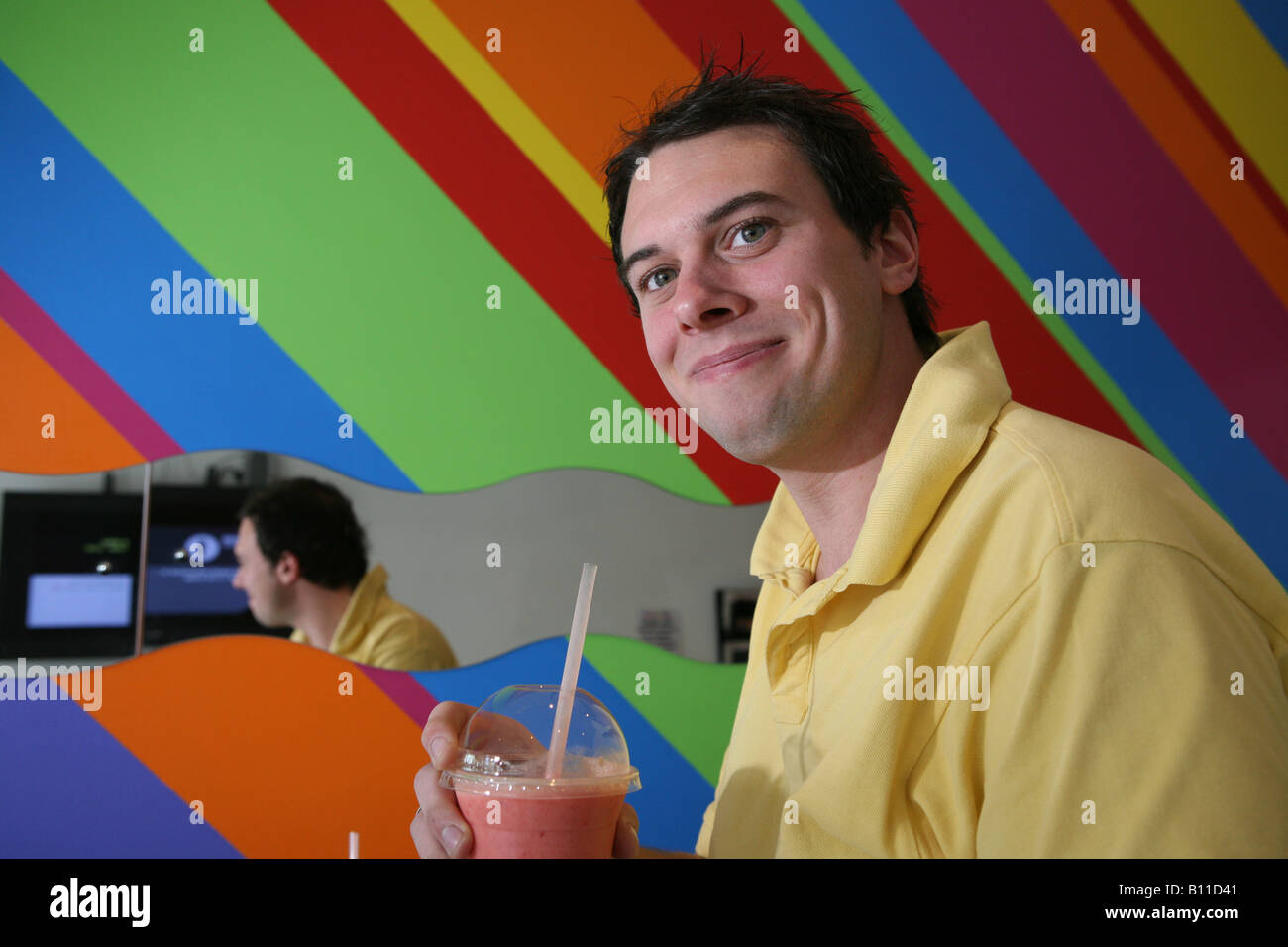 a happy male customer drinking a fruit smoothie in a smoothie bar Stock ...