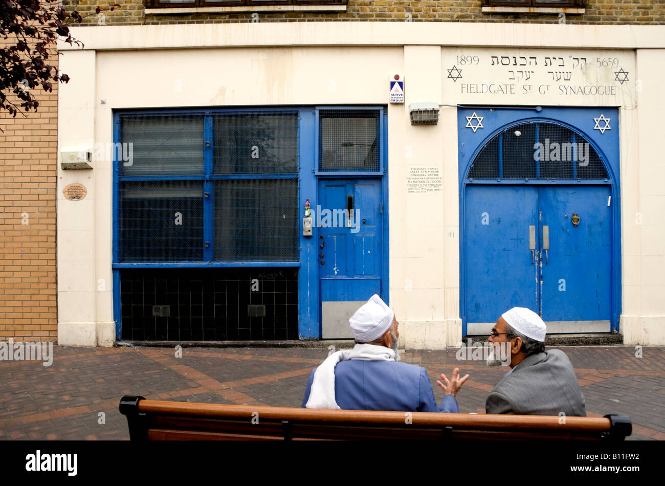 two Muslim men in conversation outside fieldgate street Great Synagogue ...