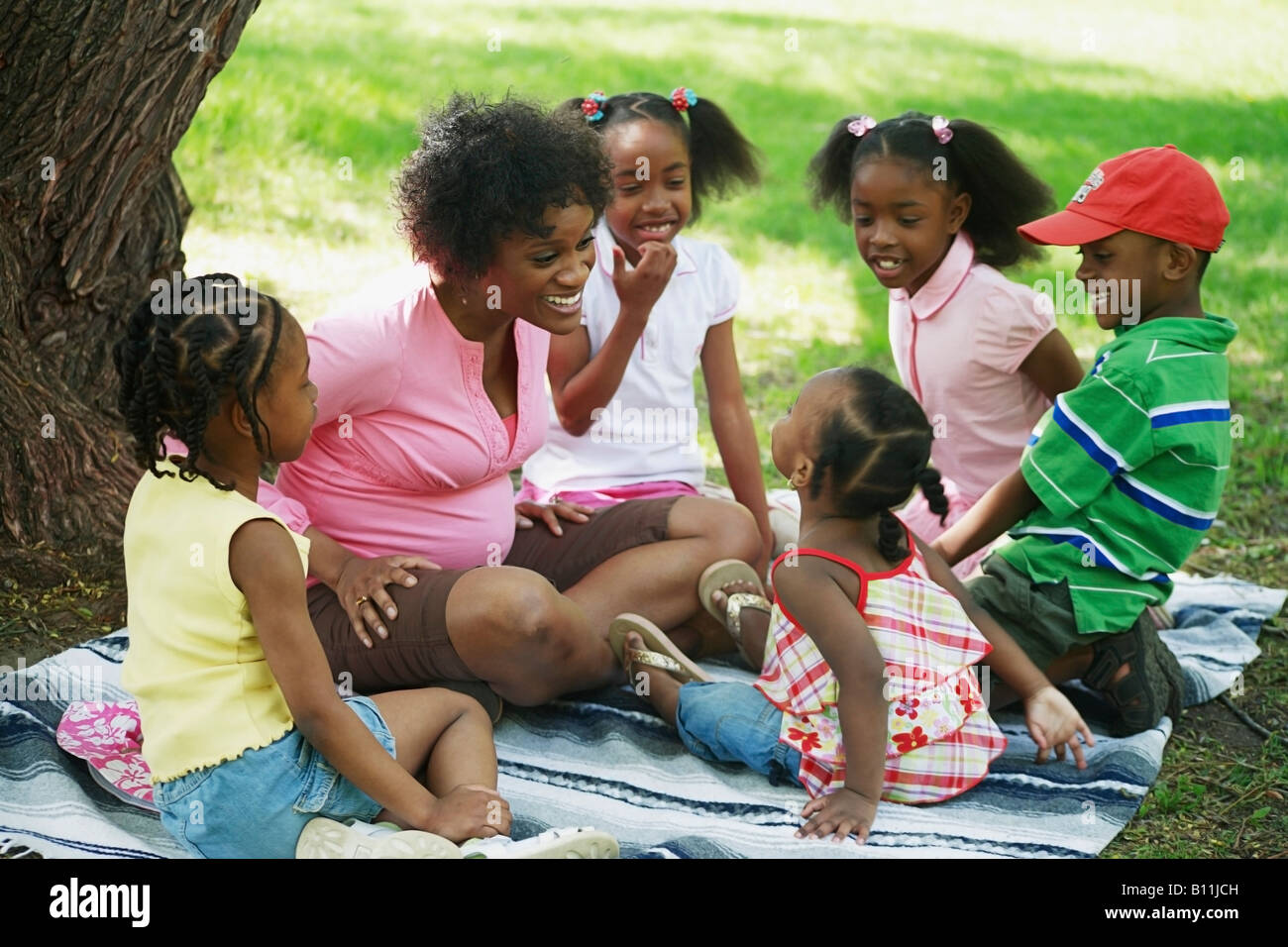 Mother with her children gathered around her at the park Stock Photo ...