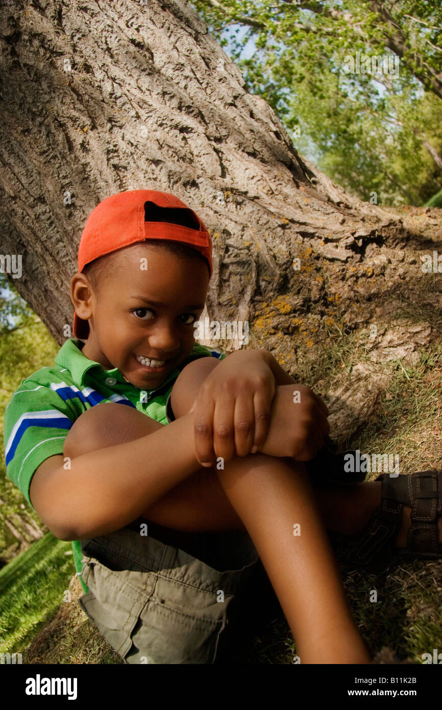 Boy sitting by a tree Stock Photo - Alamy