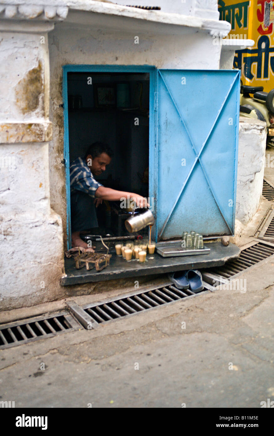 INDIA UDAIPUR Tea wallah prepares masala chai in the doorway of his ...