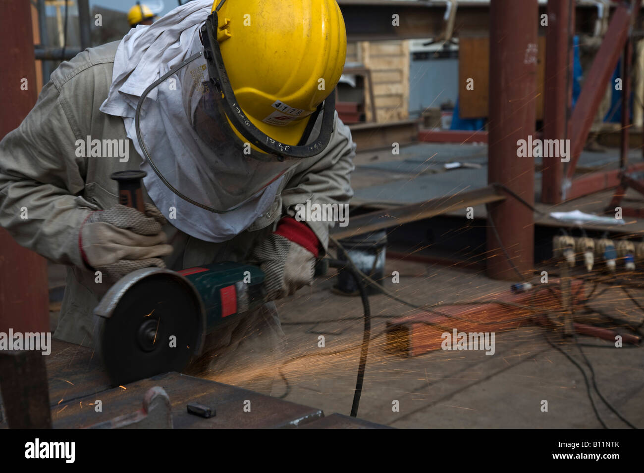 Worker sanding metal on oil platform Port Khalid Sharjah United Arab ...