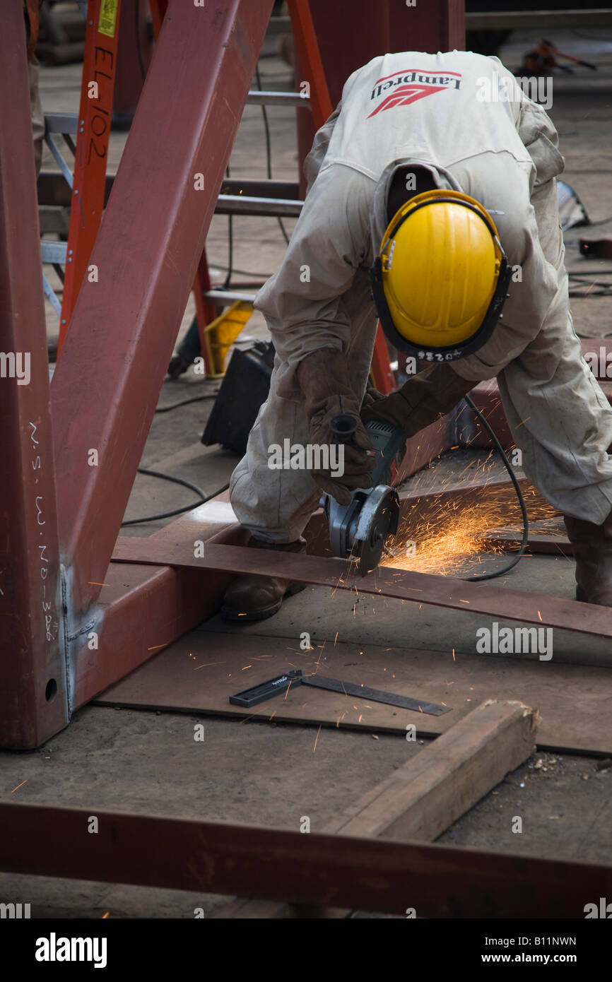 Worker sanding metal on oil platform Port Khalid Sharjah United Arab ...