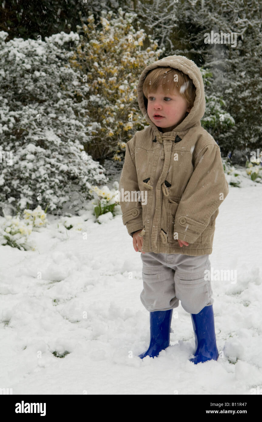 little boy, child, standing in snow looking very cold but dressed warm ...