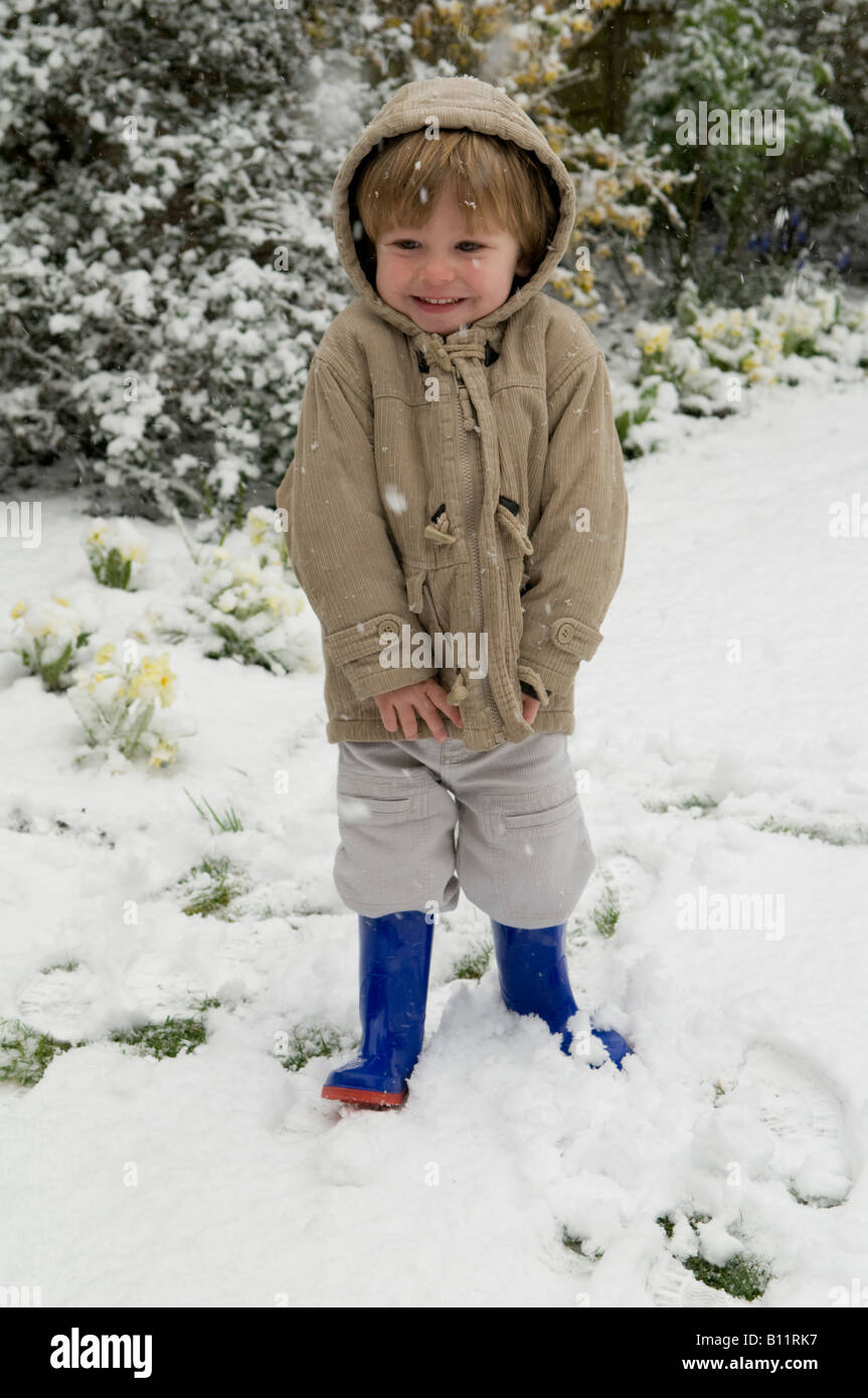 little boy, child, standing in snow looking very cold but dressed warm ...