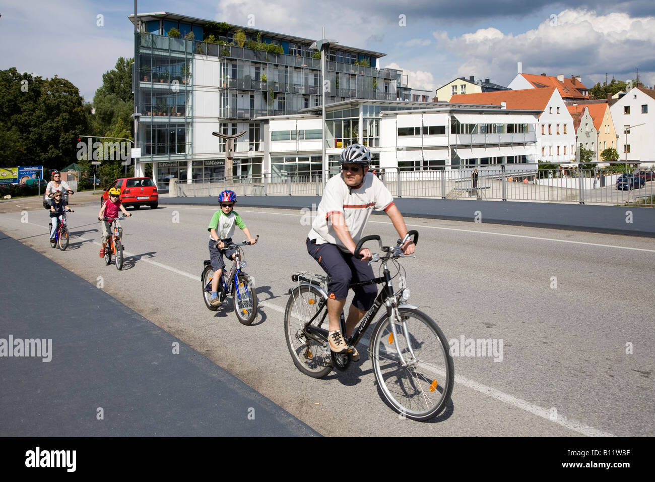 Two adults and three children cycling in cycle lane in urban setting ...