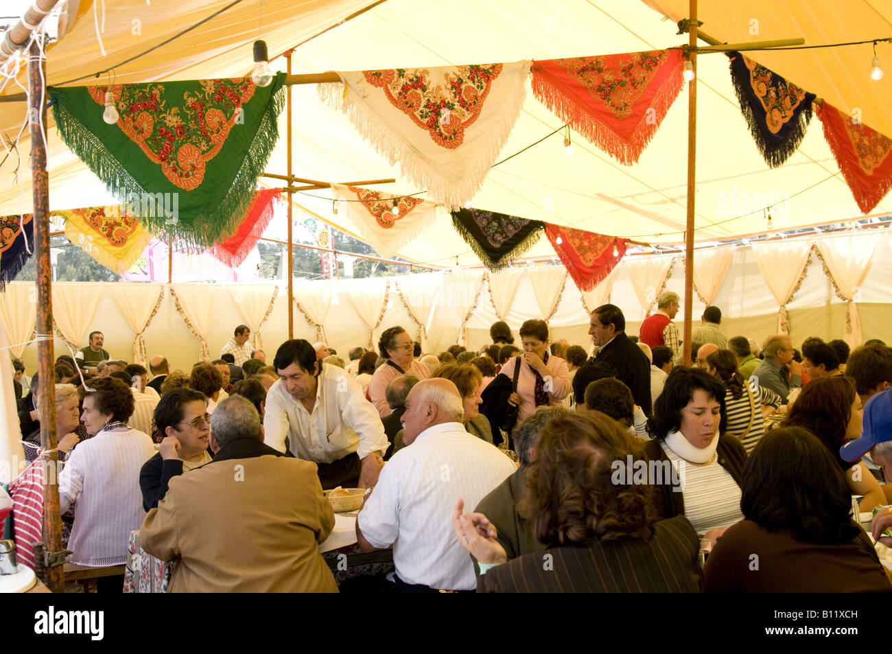 people in a temporary tent restaurant at a popular religious party ...