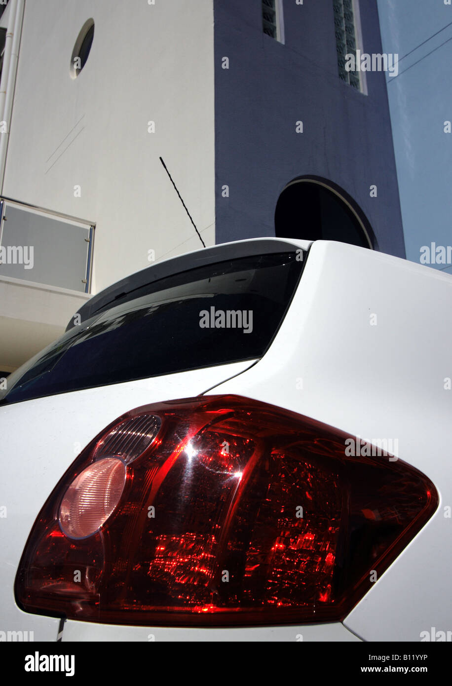 WHITE HIGHRISE BUILDING WITH RED CAR TAILIGHT AND WHITE CAR IN ...