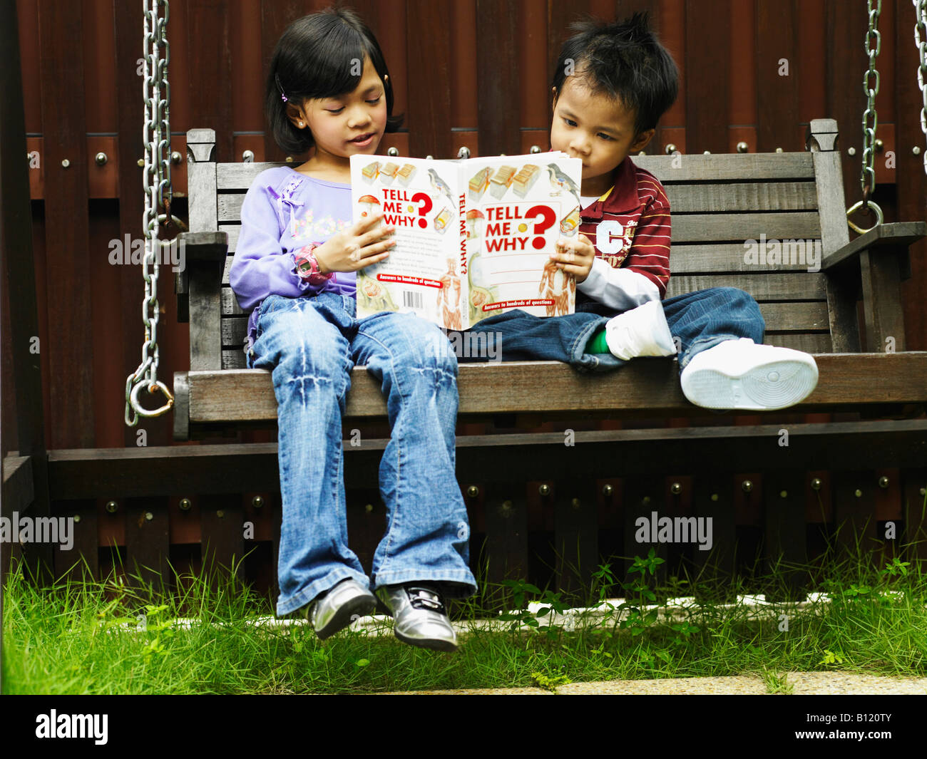 Children on the swing reading book Stock Photo - Alamy