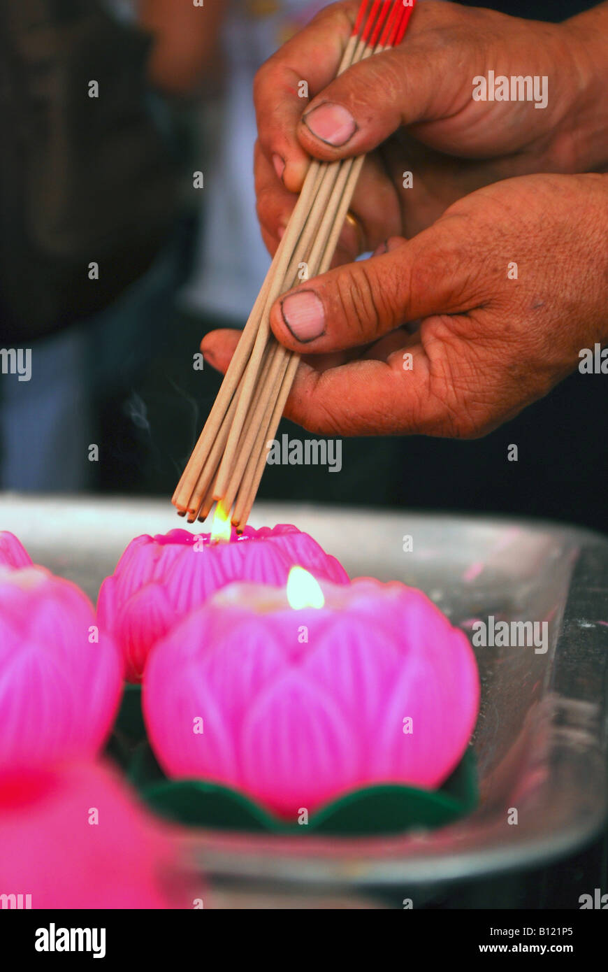 Closeup of hands holding joss sticks lighting up Stock Photo - Alamy