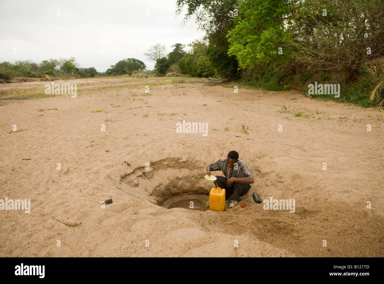 Young man pouring drinking water into a container from the water ...