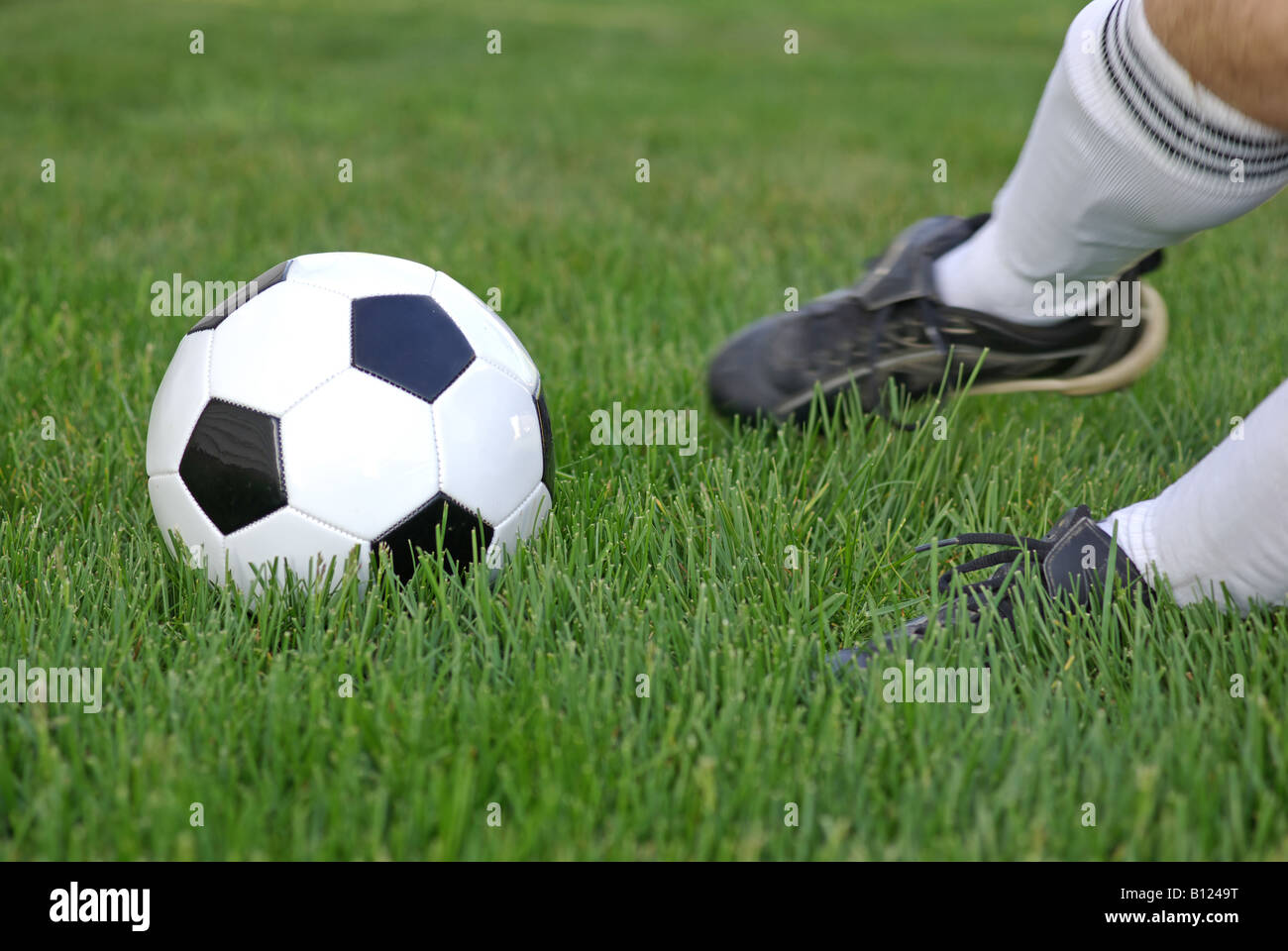 Soccer player kicking the ball in the grass Stock Photo - Alamy