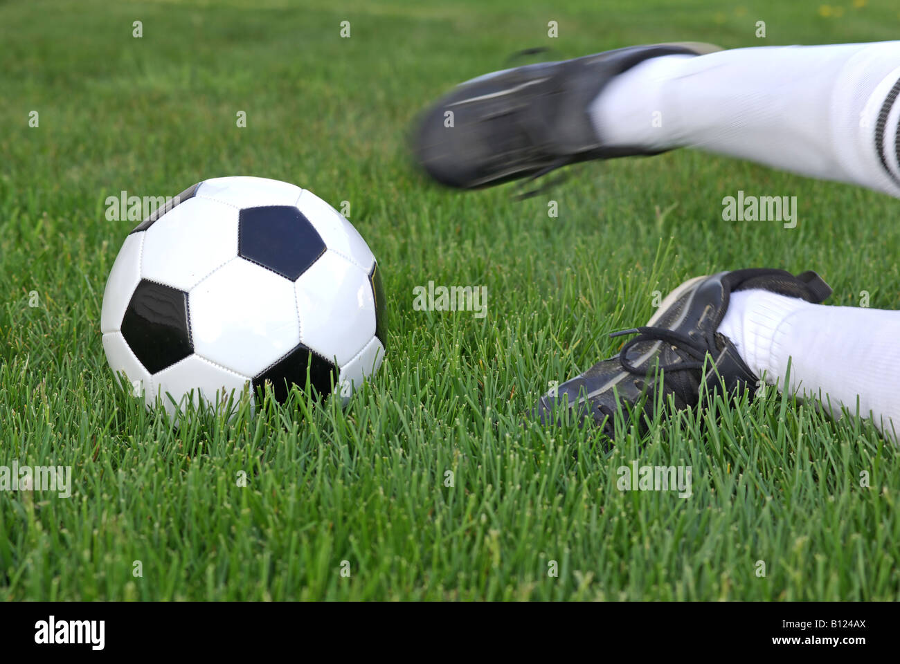 Soccer player kicking the ball after a fall Stock Photo - Alamy