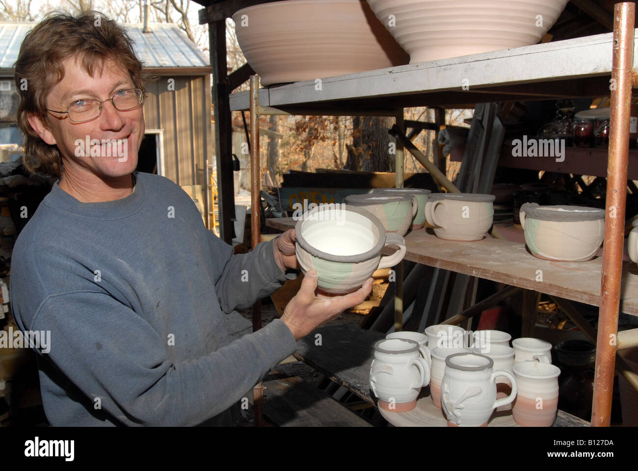Potter showing unfired ceramic piece about to be loaded into a kiln ...