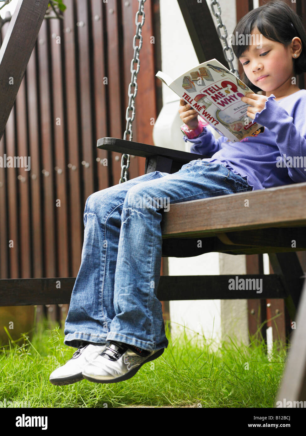 Sitting on swing, reading book Stock Photo - Alamy