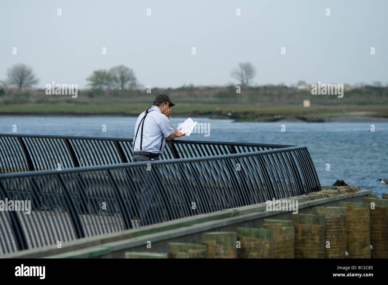 A man overlooking a river reads a book Stock Photo - Alamy