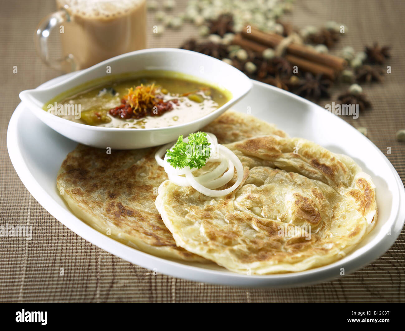 a plate of roti canai, a glass of teh tarik and curry Stock Photo - Alamy