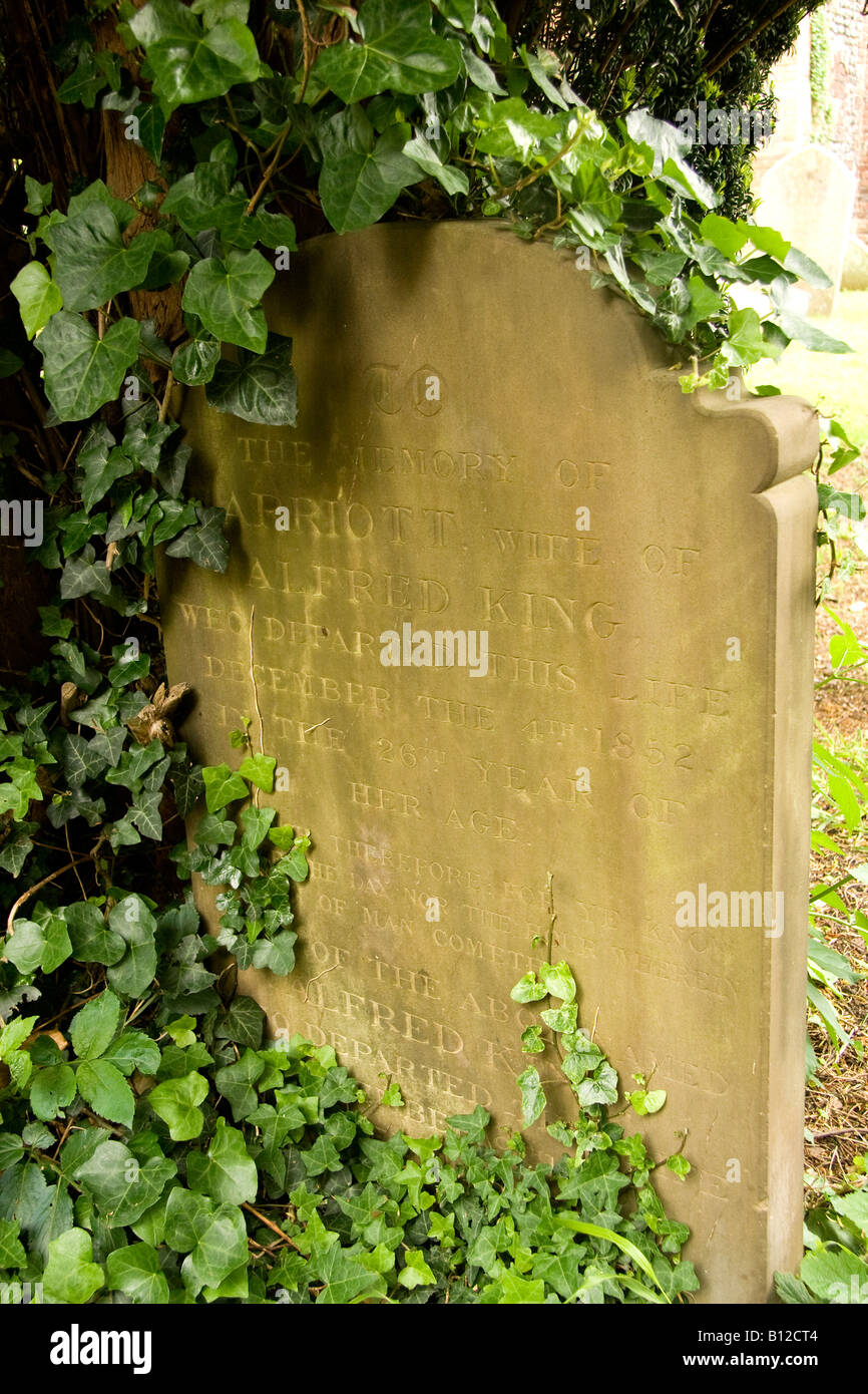 Victorian stone grave headstone overgrown with weeds in a church ...