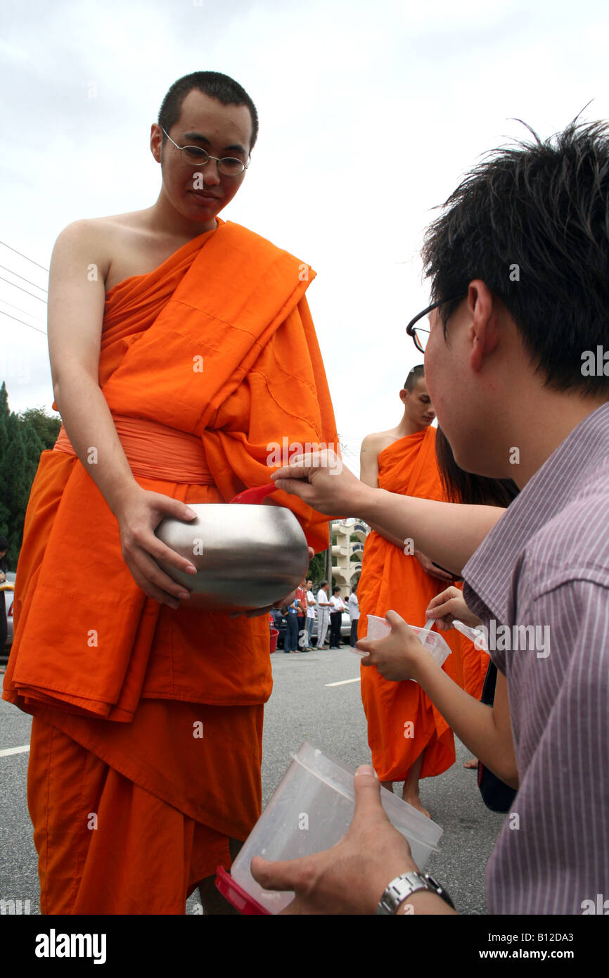 Buddhist monks receiving alms from devotees Stock Photo - Alamy