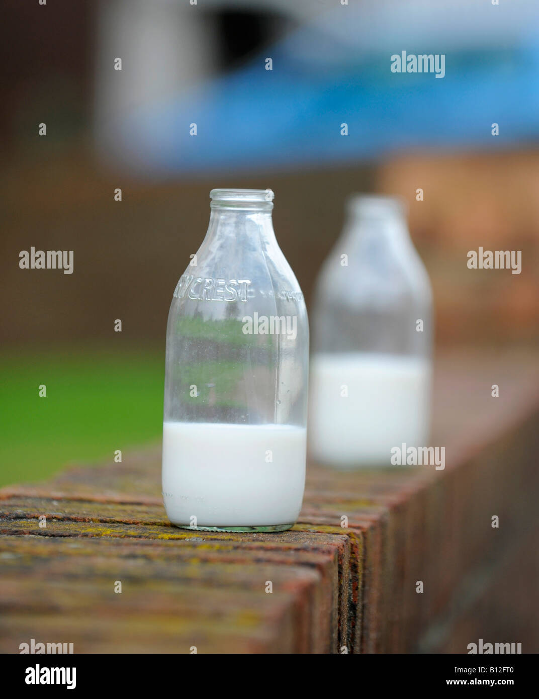 Two partially drunk bottles of milk outside on a wall Stock Photo - Alamy