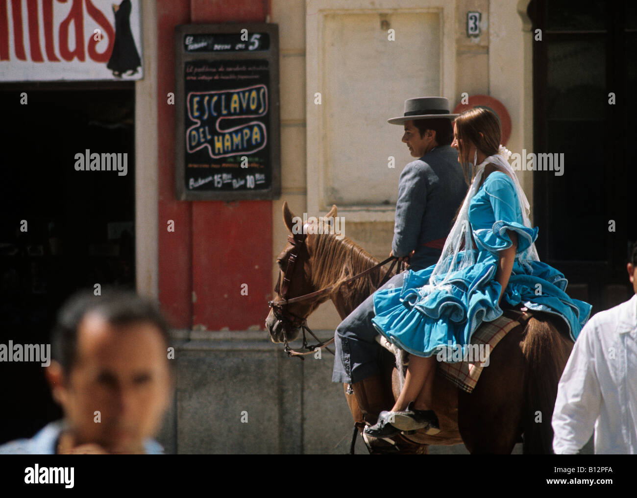 Senorita wearing flamboyant festival dress is riden to the bullfight on ...