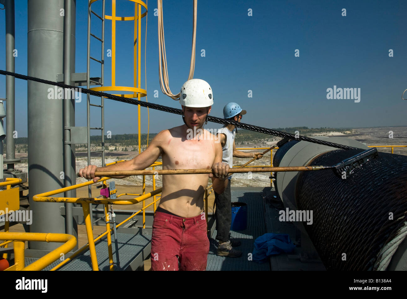 Workers greasing cables on a 60m high dragline in a Brown coal surface ...