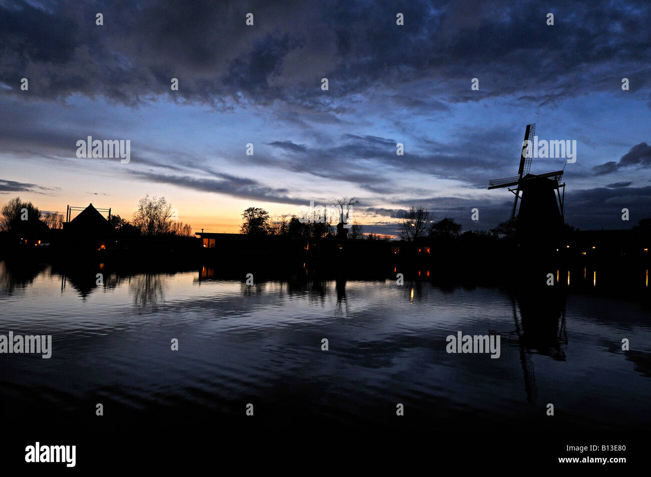 Traditional Dutch windmill and heavy clouds reflecting in Vecht river ...