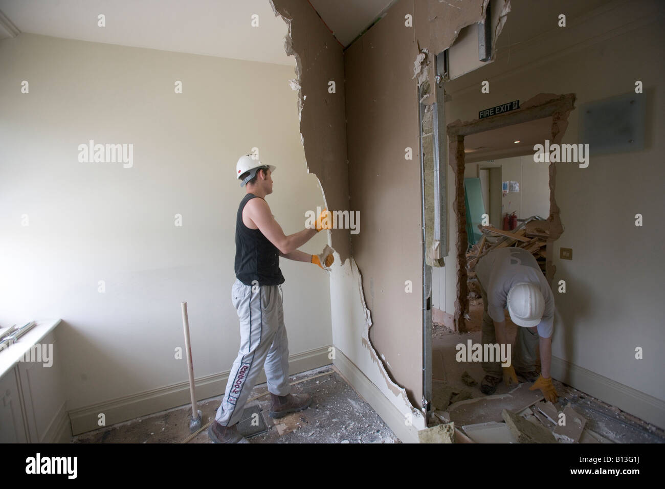 A workman pulls down a piece of plasterboard on a demolition site Stock ...