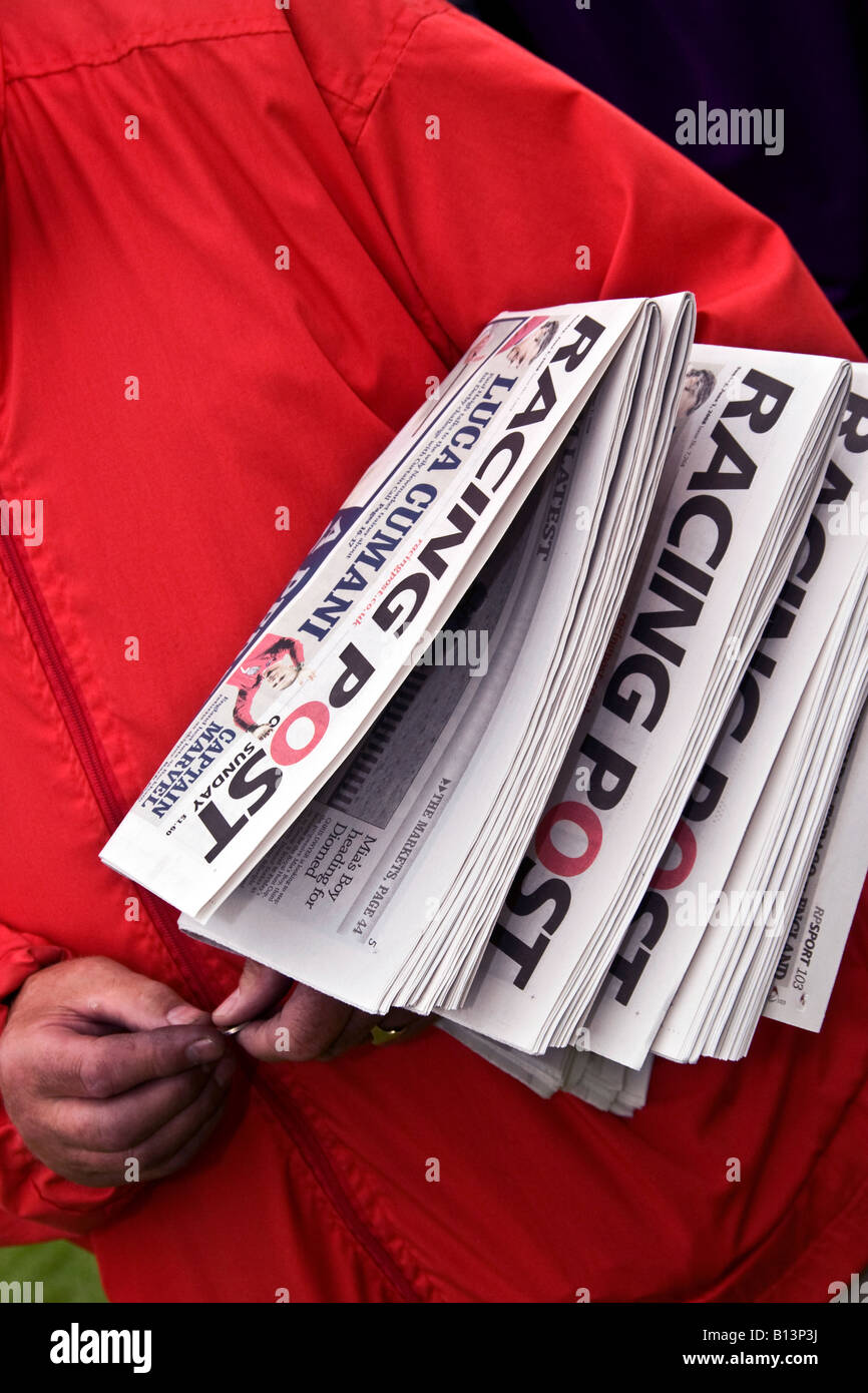 Man with red weather proof jacket selling the Racing Post newspapers ...